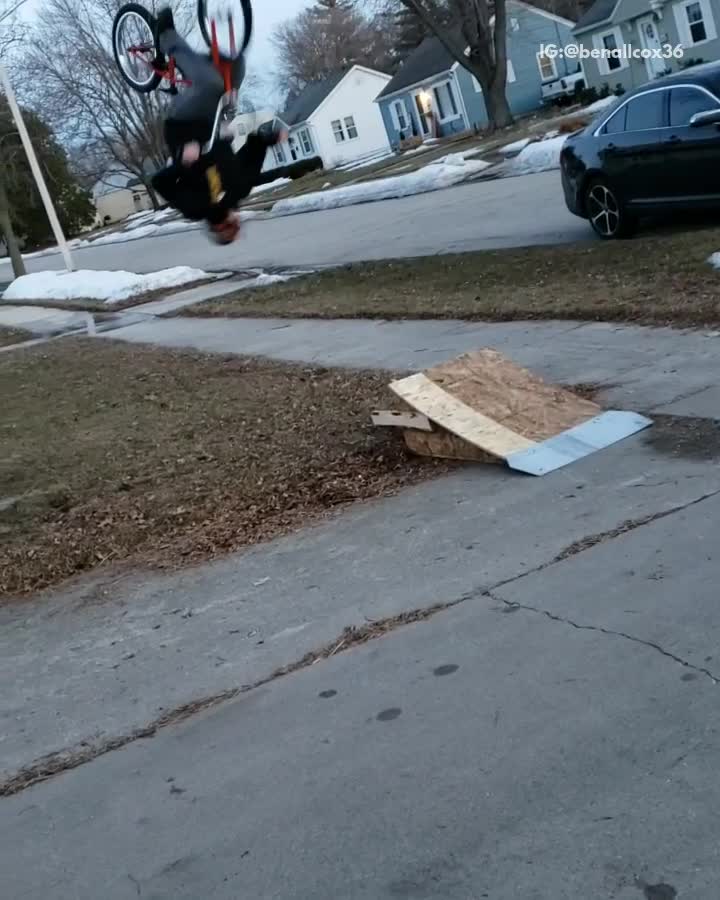 Kid does a backflip off small wooden ramp on his red bike, lands on ...