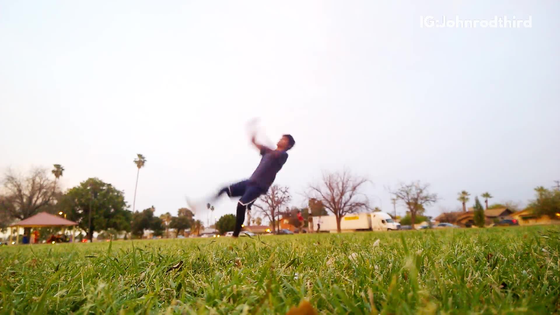 Shoeless guy tries to flip on grass lands and emoji face