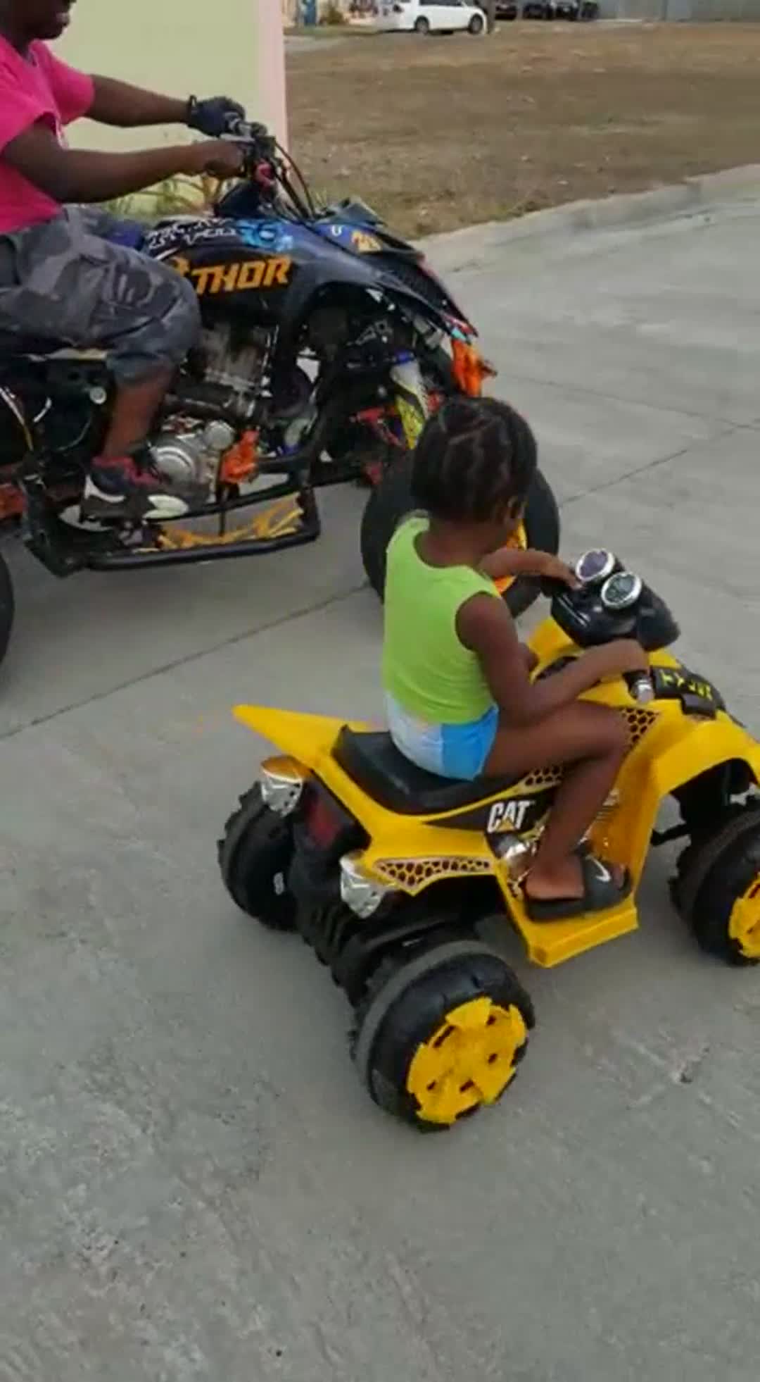 A Toddler learns to drive four Wheeler with his dad